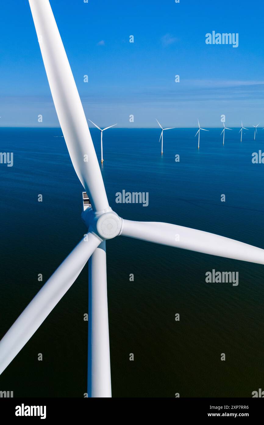 Sleek wind turbine blades spin gracefully above sparkling waters ...