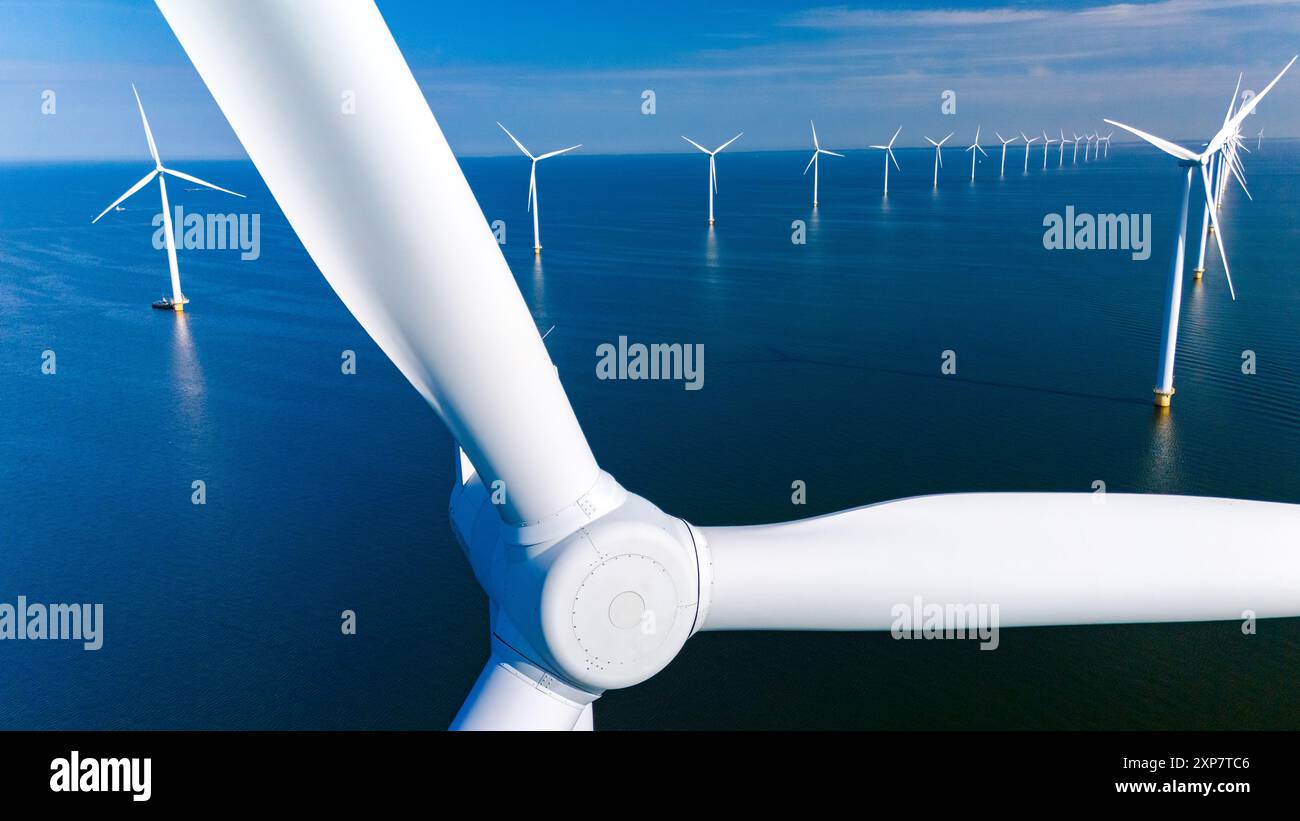 Vast wind turbines rotate gracefully above the calm sea, capturing ...