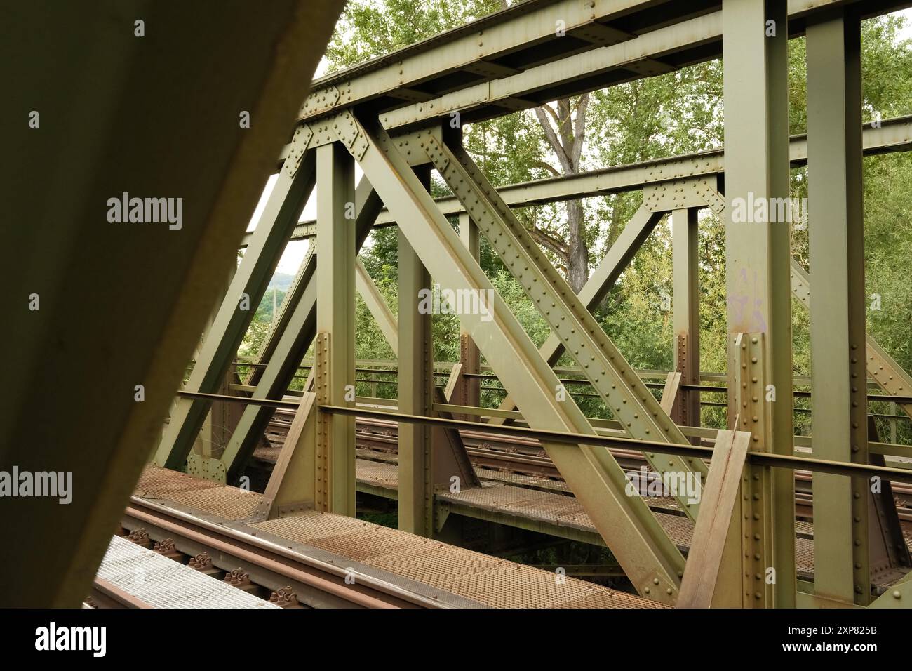An old railroad bridge with a steel structure and trees in the ...