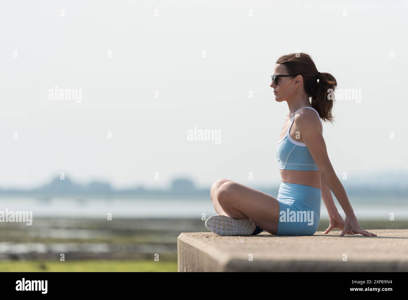 sporty woman sitting crossed legged resting after exercise outdoors ...