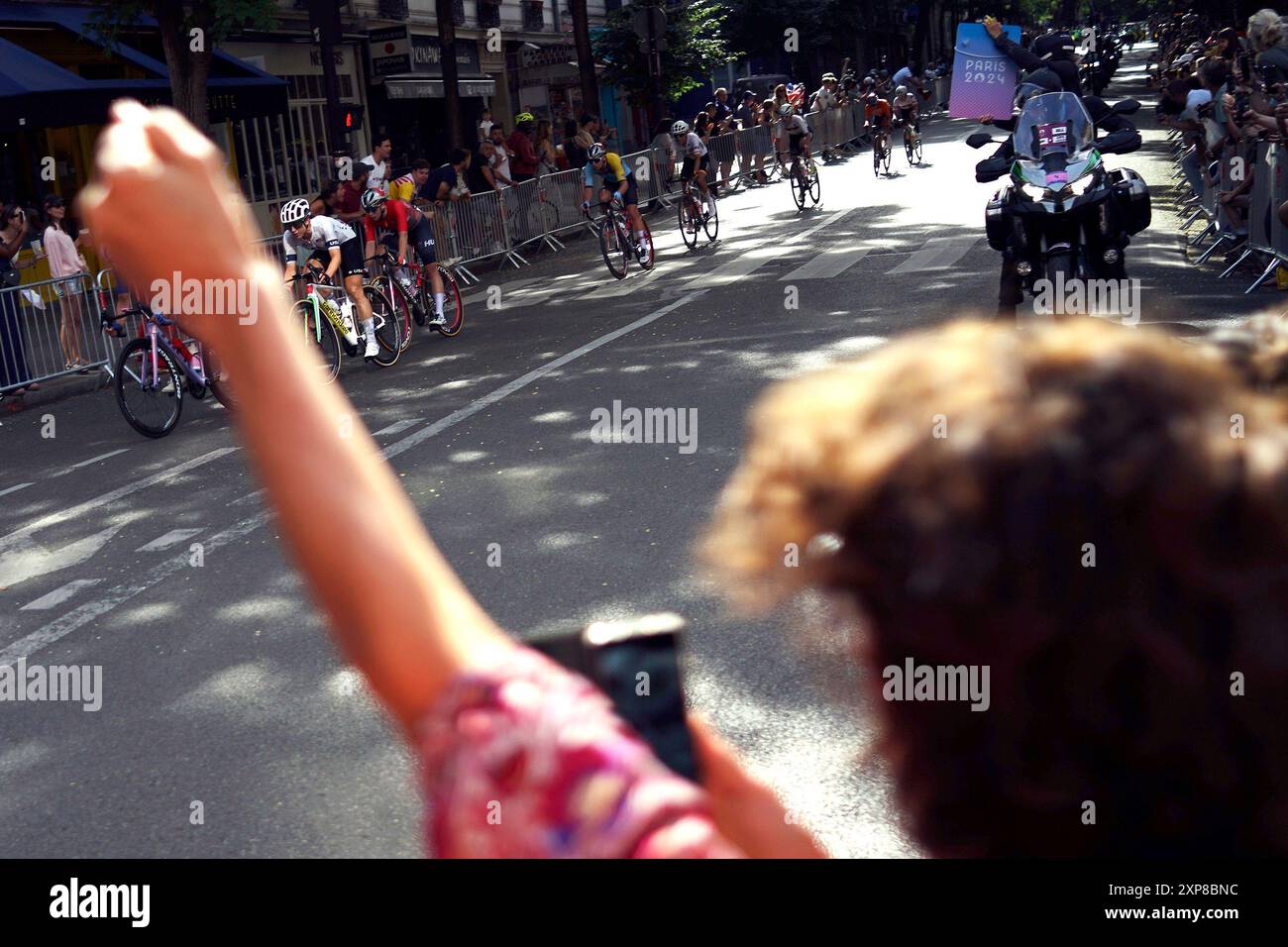 Spectators cheer the competitors riding on a street during the women's ...