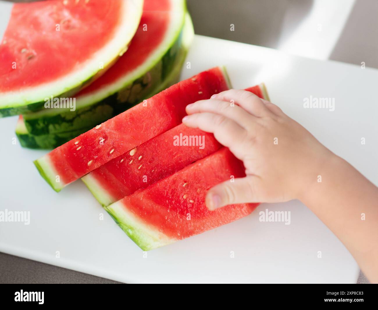 a child takes a piece of watermelon with his hand Stock Photo - Alamy