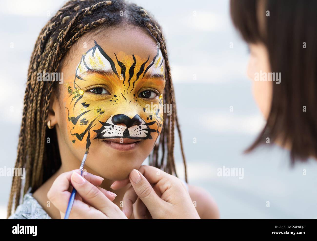 Little girl getting her face painted by face painting artist Stock ...