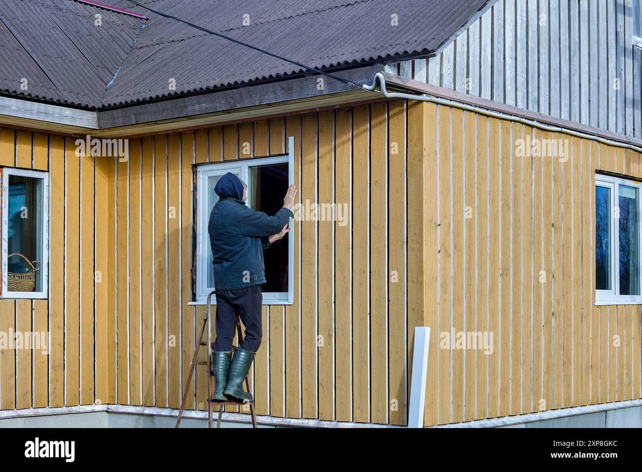 Finishing of frame and panel rural house on facade side, roofer ...