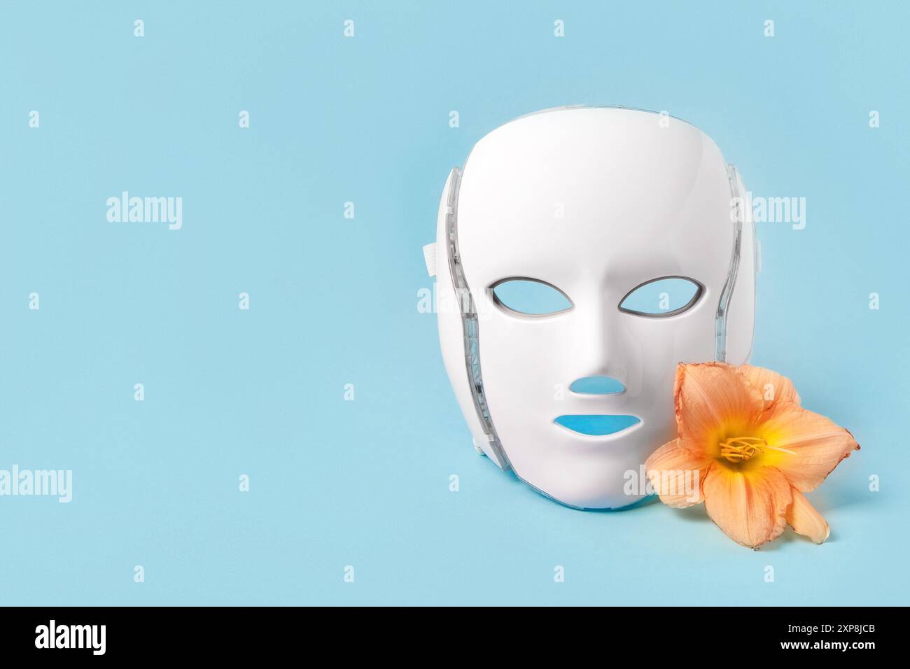 Cosmetic LED facial mask regenerative treatment on blue background with ...