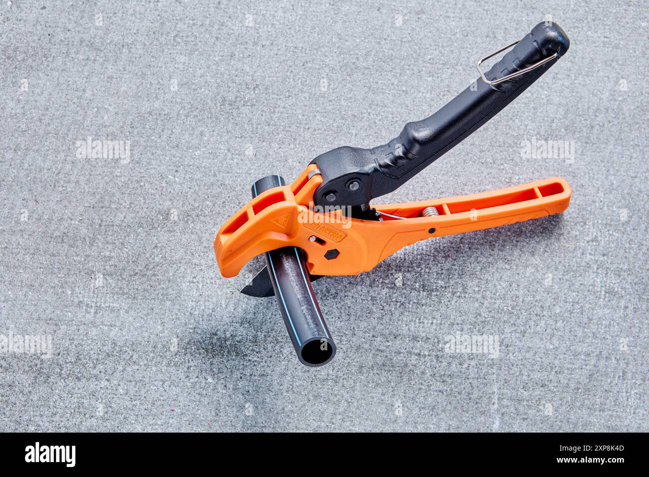 Piece of plastic pipe lies between blades of pipe cutter with ...