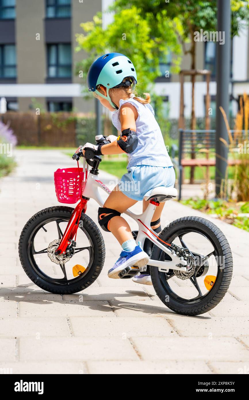 Little girl rides a two-wheeled bicycle Ii the courtyard of apartment ...