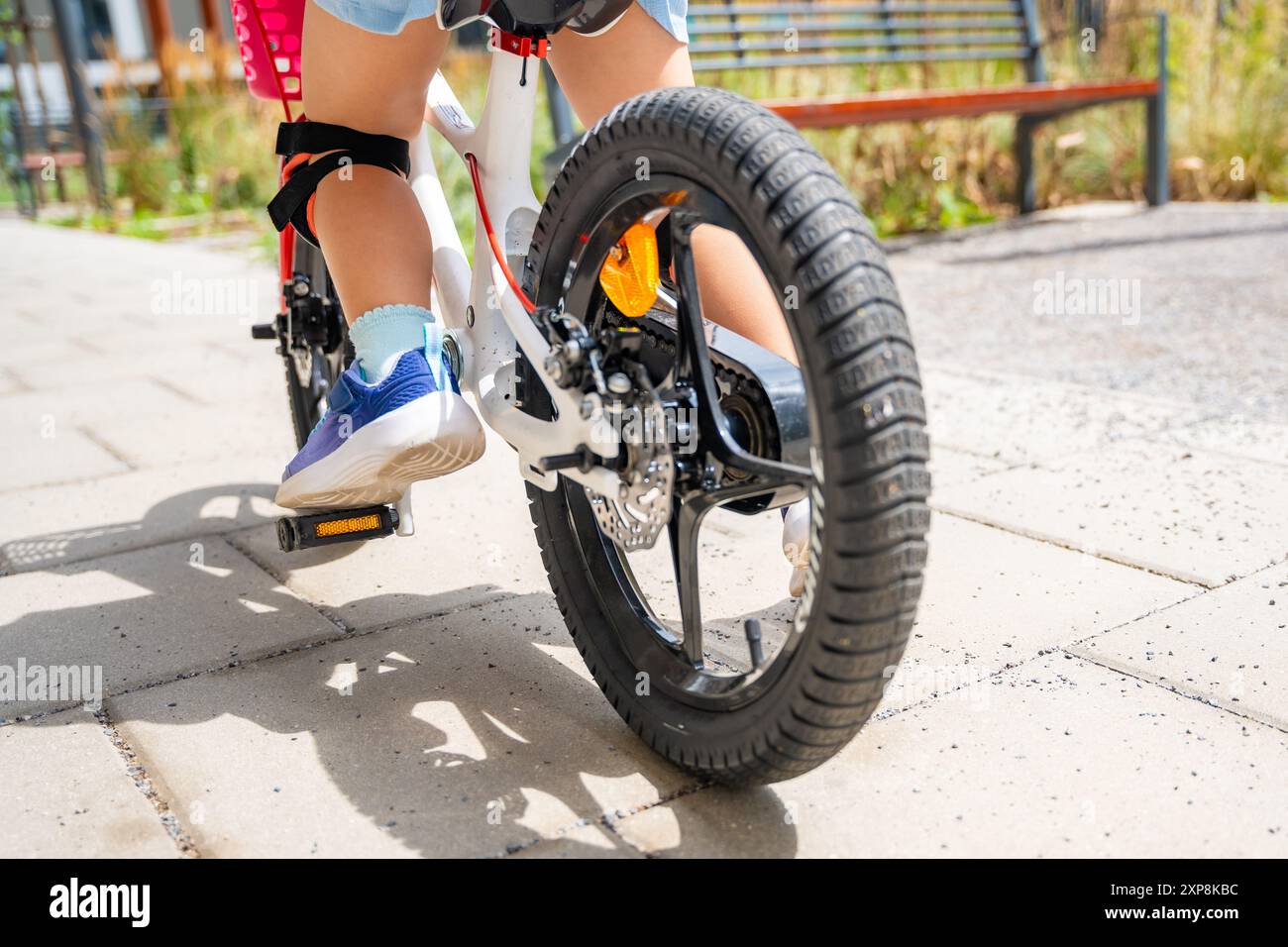Close up view of legs of little girl rides a two-wheeled bicycle Ii the ...
