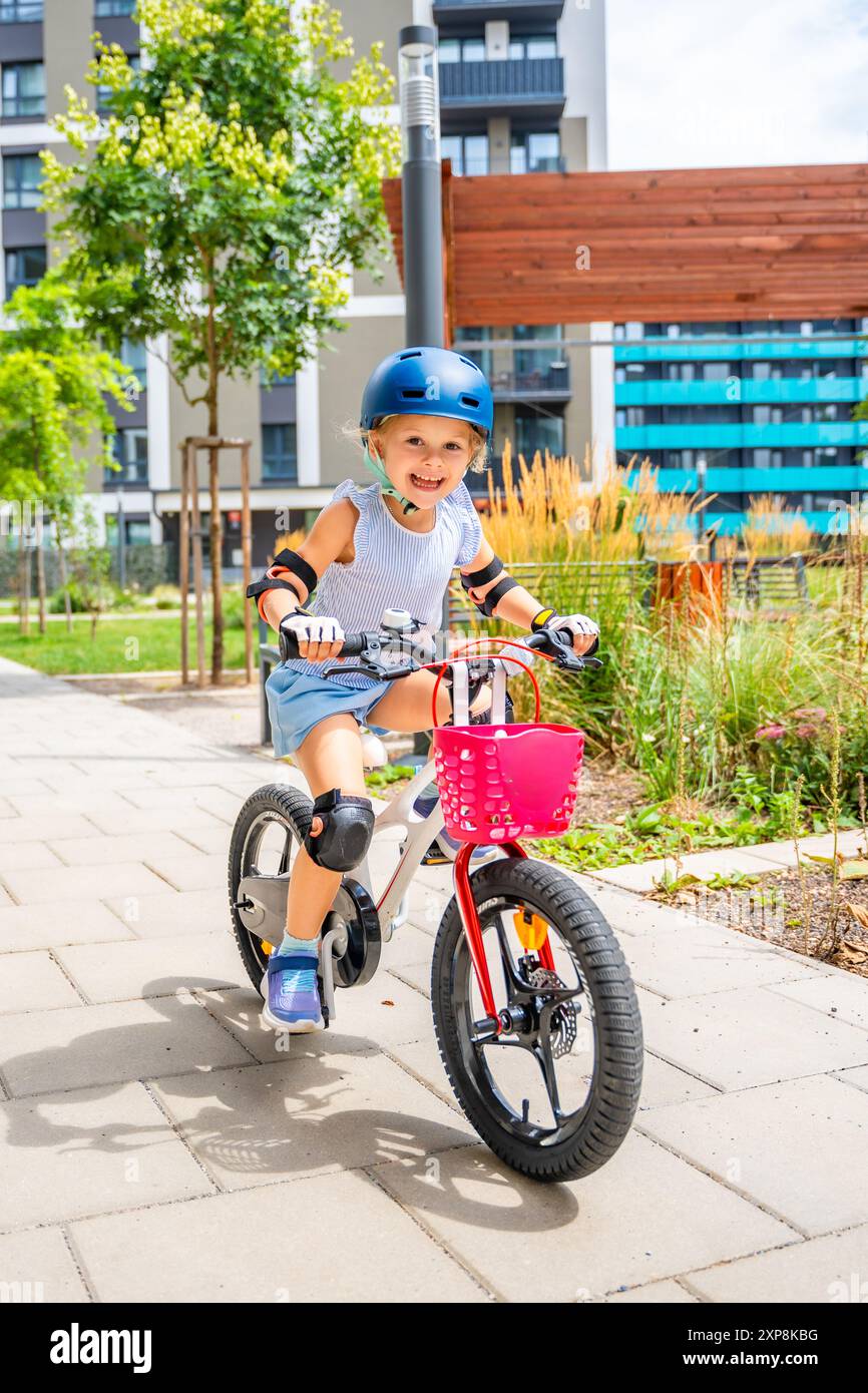 Little girl rides a two-wheeled bicycle Ii the courtyard of apartment ...