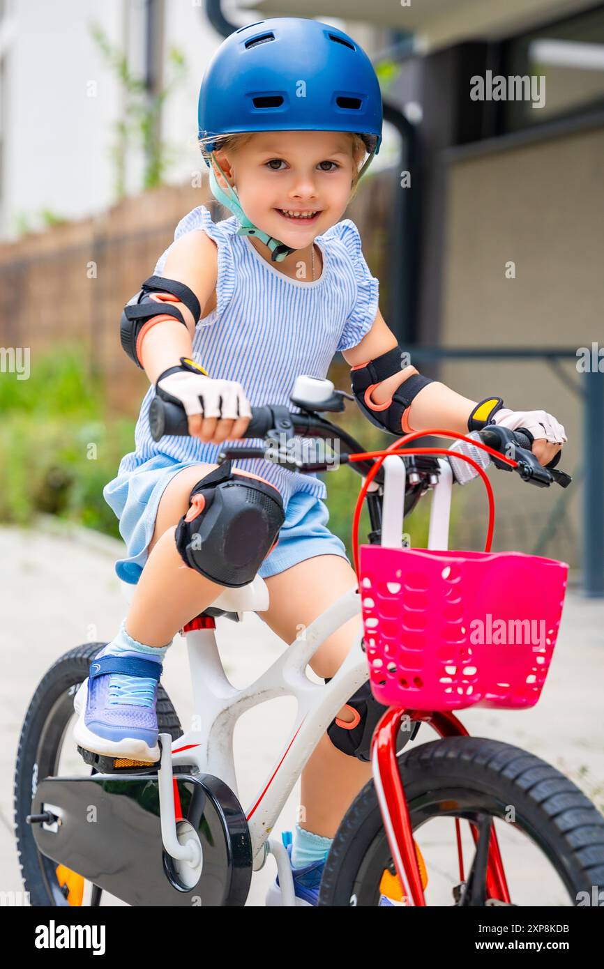 Portrait of little girl rides a two-wheeled bicycle Ii the courtyard of ...