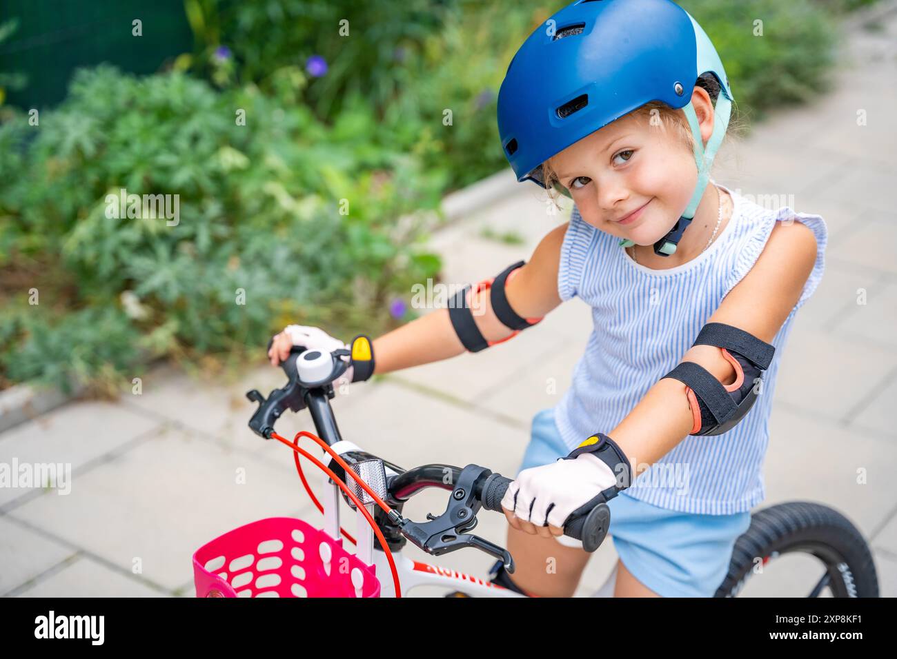 Portrait of little girl rides a two-wheeled bicycle Ii the courtyard of ...