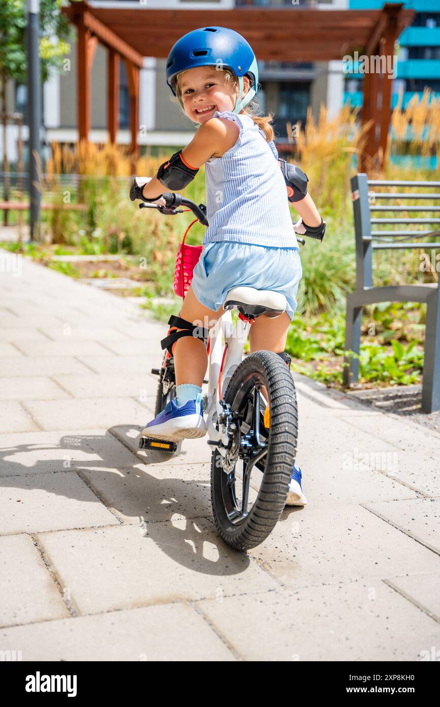 Little girl rides a two-wheeled bicycle Ii the courtyard of apartment ...