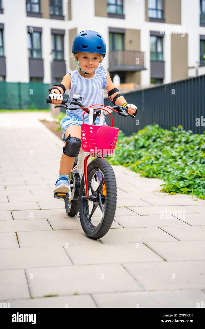 Little girl rides a two-wheeled bicycle Ii the courtyard of apartment ...