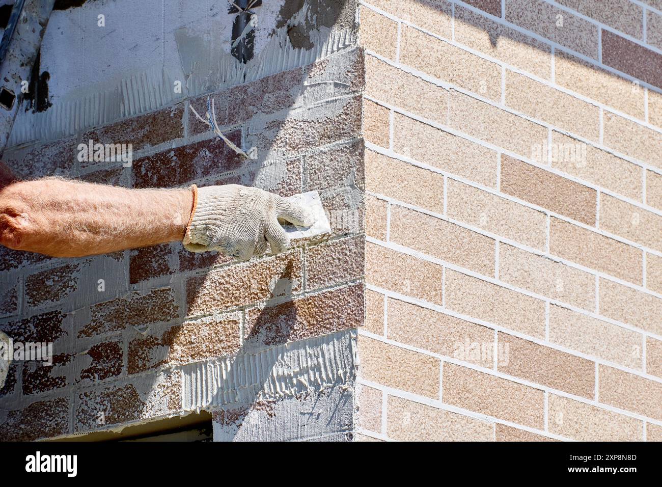House painter removes excess adhesive from surface of marble chip faux ...