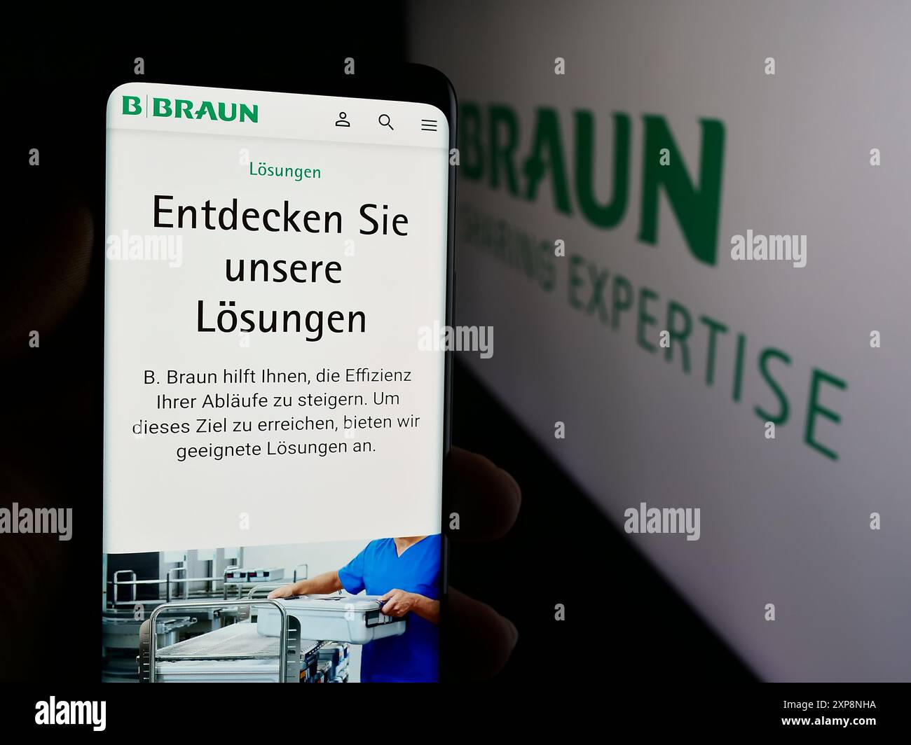 Person holding cellphone with web page of Germany pharmaceutical device ...