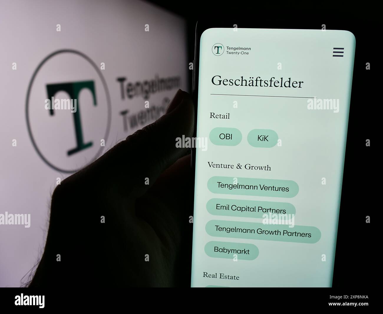 Person holding cellphone with website of German holding company ...