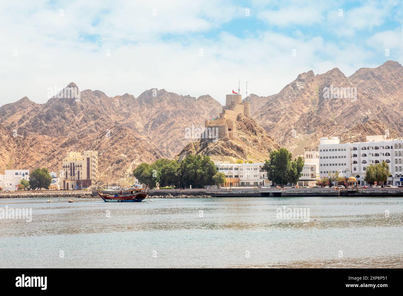 Promenade panorama with Mutrah castle on the hill and traditional dhow ...