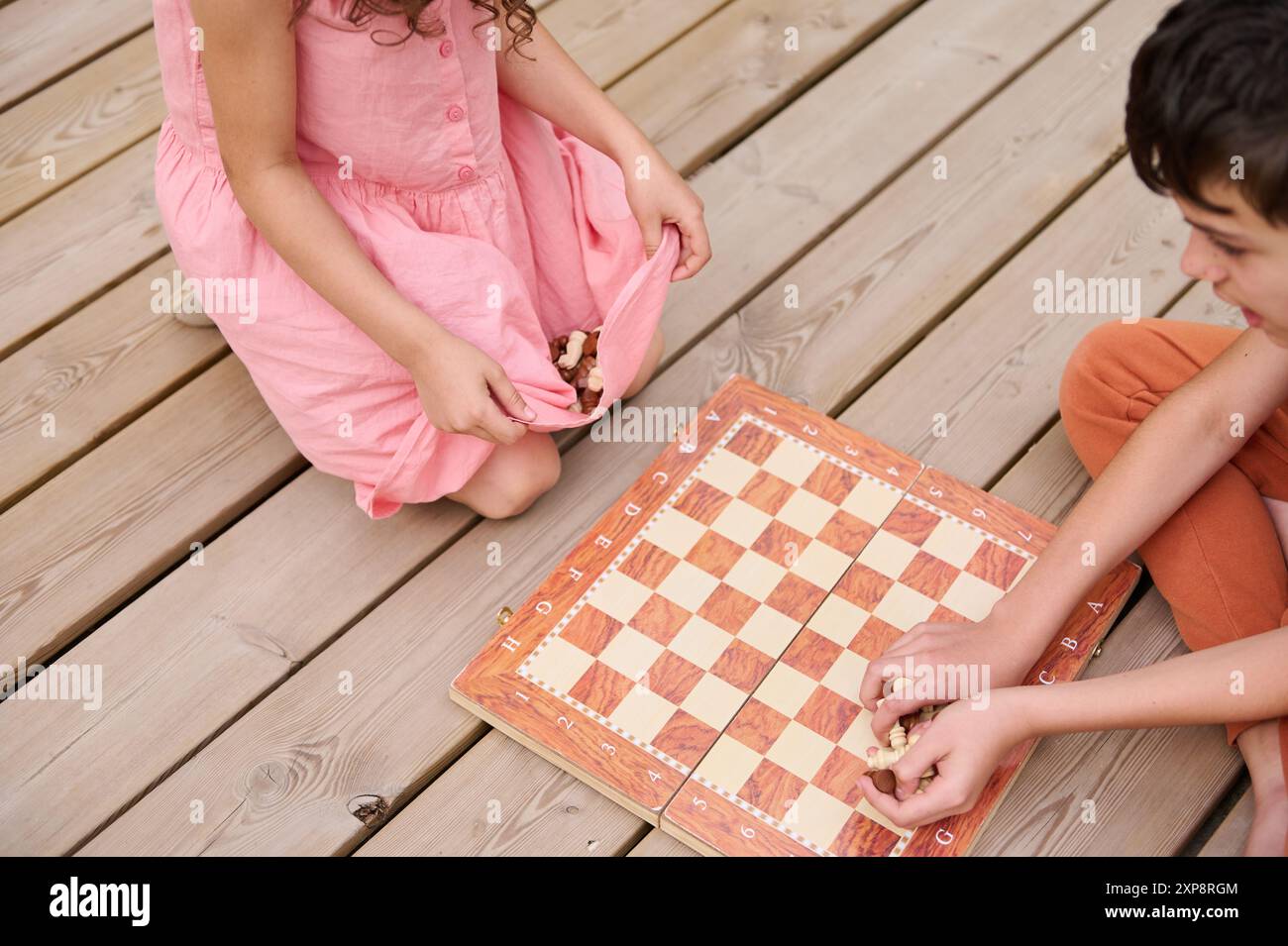 Two children enjoying a game of chess on a wooden deck, highlighting ...