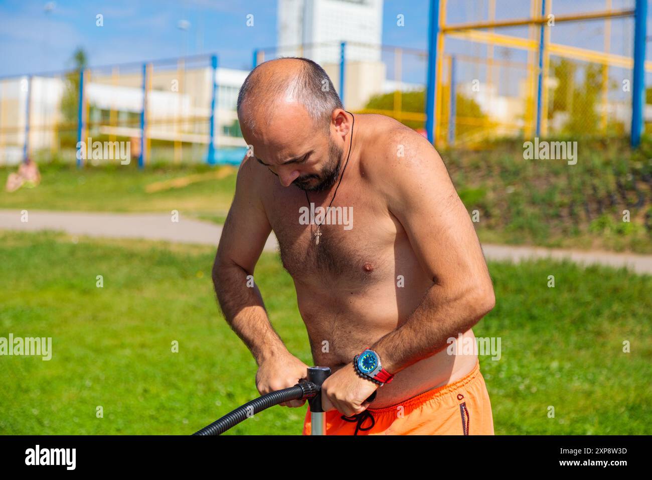 A focused man uses a pump to inflate a SUP board Stock Photo - Alamy