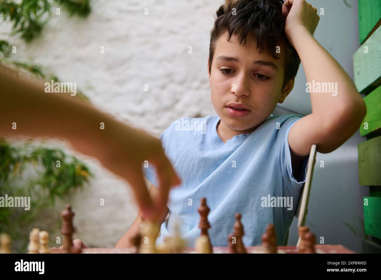 Young boy concentrating and thinking hard while playing chess outside ...