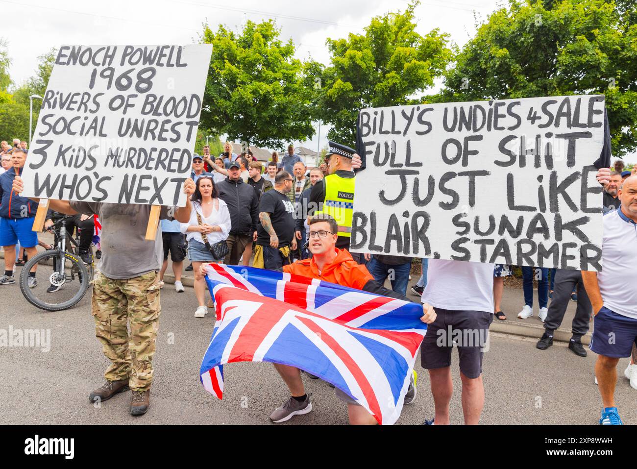 Rotherham, UK. 04 AUG, 2024. Men hold signs referencing Enoch Powell as ...