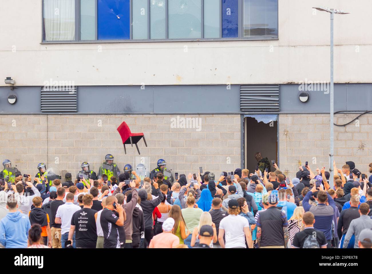 Rotherham, UK. 04 AUG, 2024. Rioters throw a chair as they smash glass ...