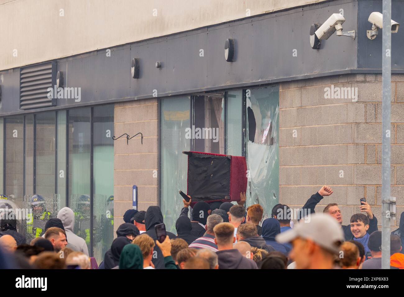Rotherham, UK. 04 AUG, 2024. Rioters throw a chair to smash glass and ...