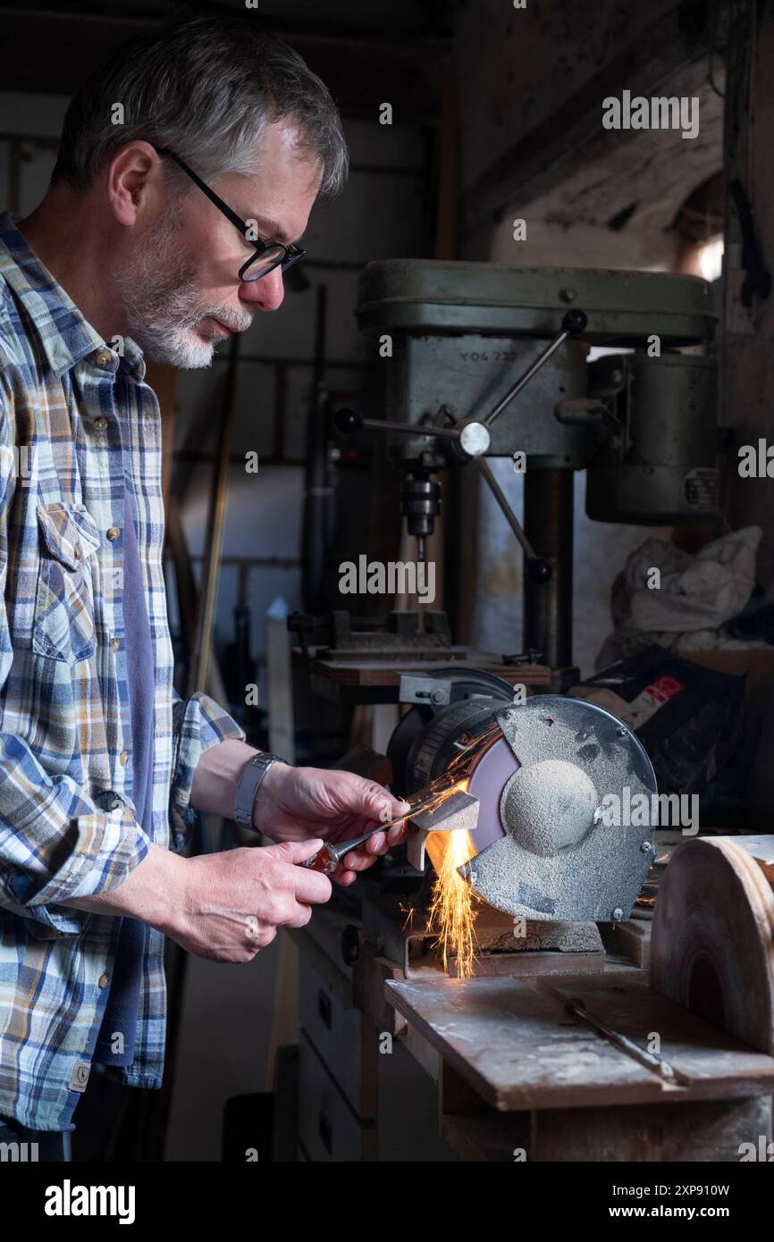 DIY man sharpening a chisel in a workshop Stock Photo - Alamy
