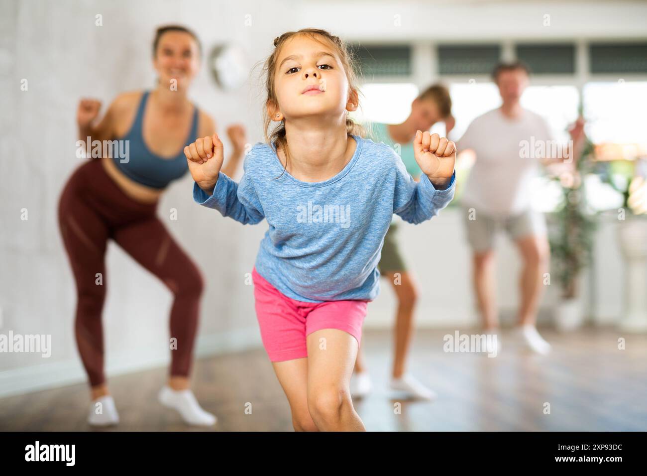 Cute little girl practicing dance movements with her family members ...