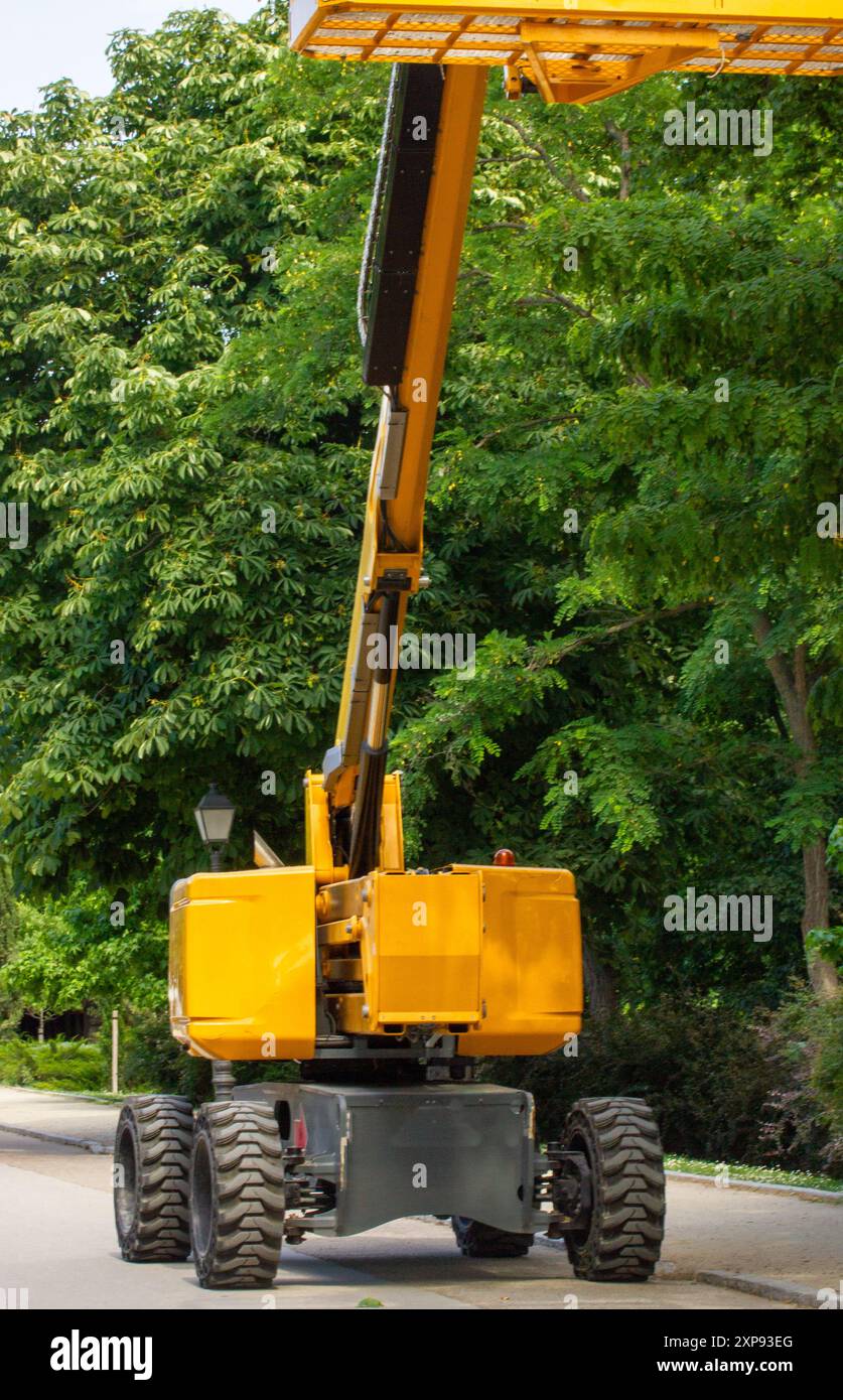 High yellow lift crane with platform for garden works, trees care. Cutting tree on a high ...