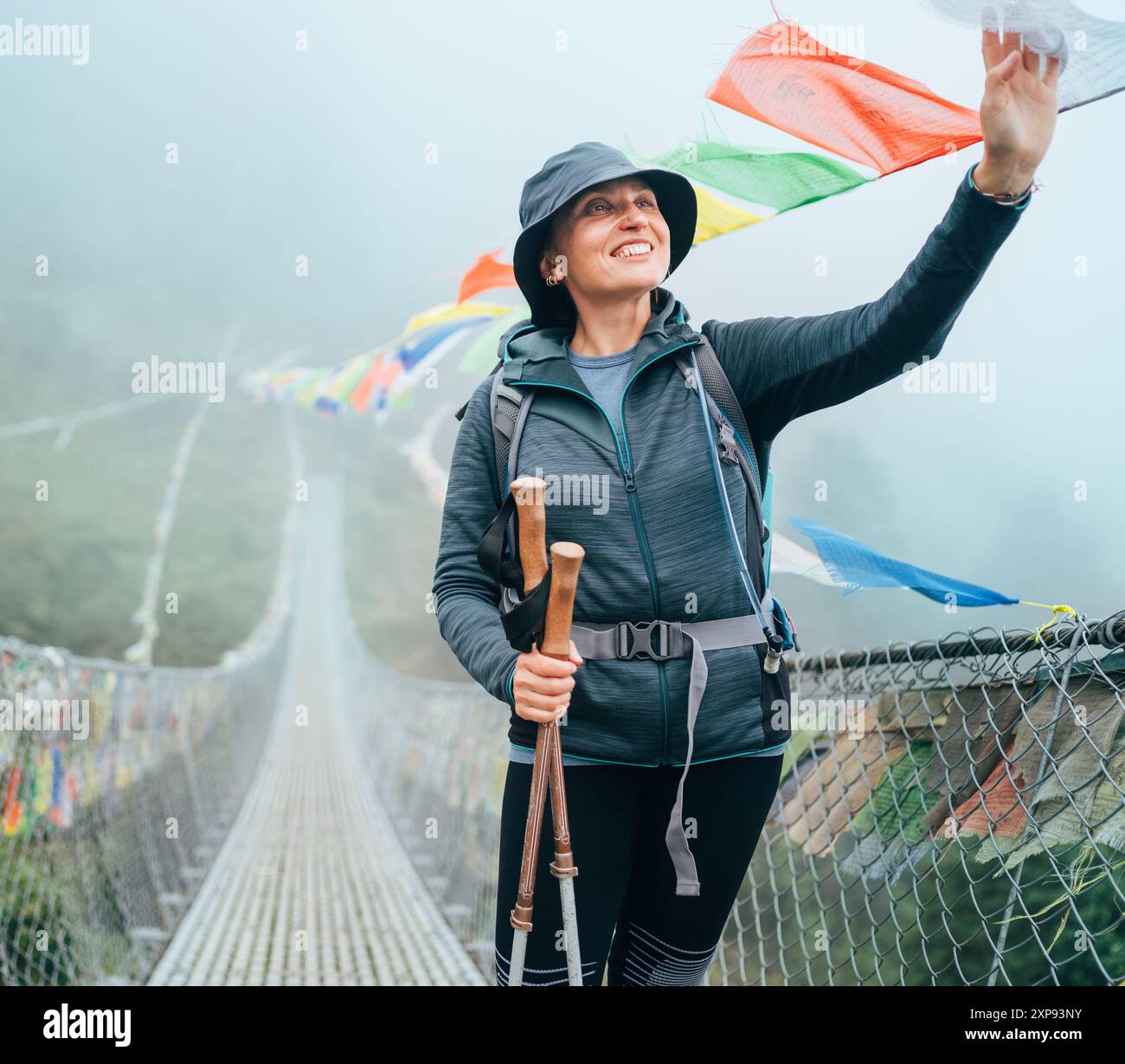 Young smiling female crossing canyon over Suspension Bridge and ...