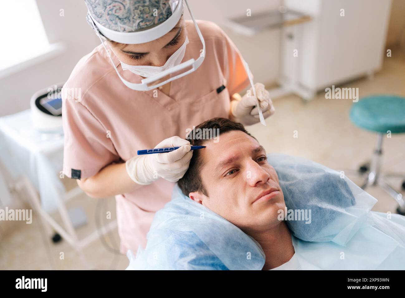 Top view of female trichologist doctor marking hair line to male ...
