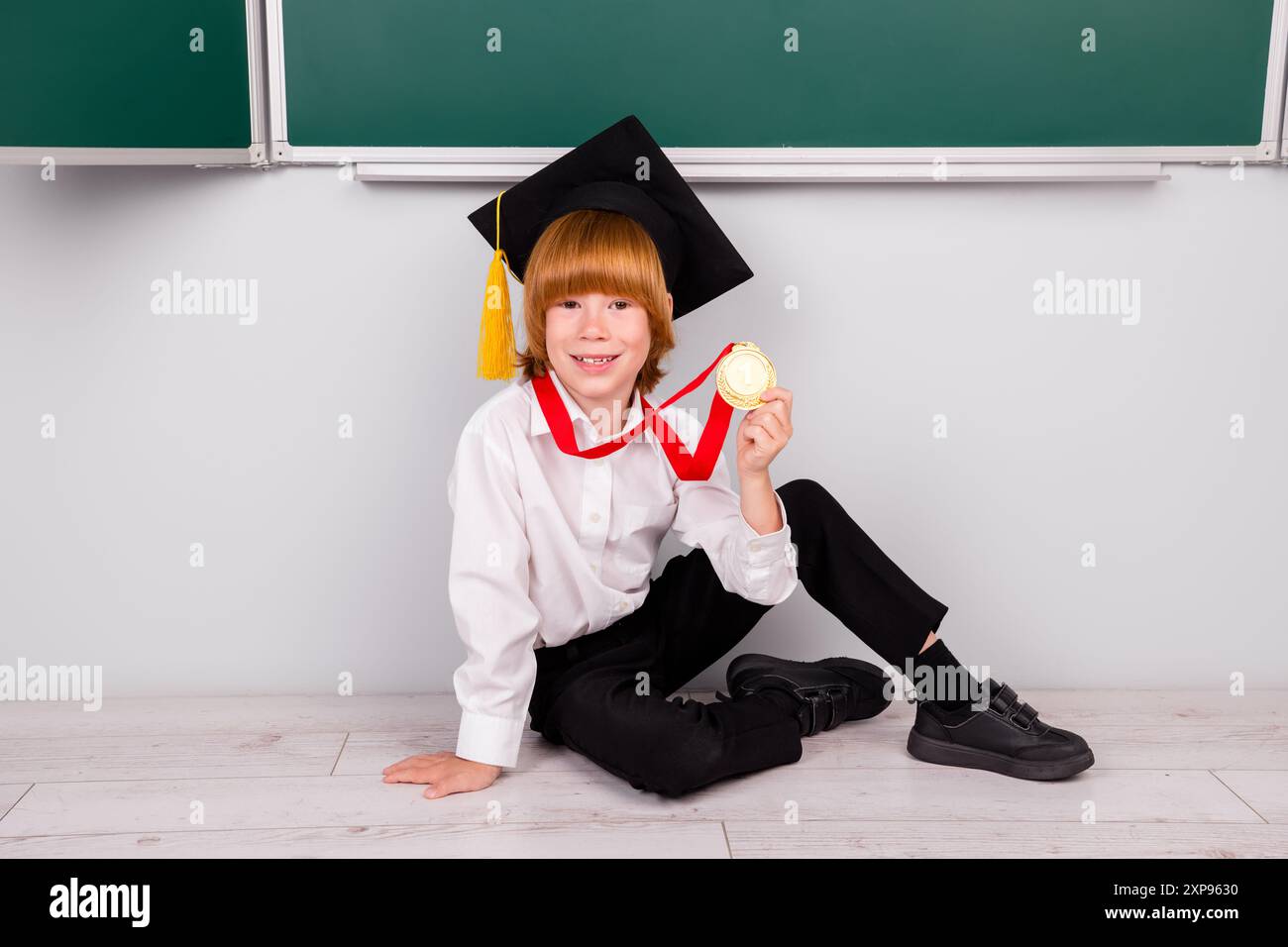 Full size photo of charming little pupil boy sit floor graduation win ...