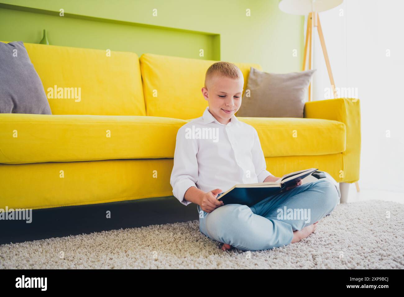 Full length photo of cute adorable boy sit floor read book pupil remote ...