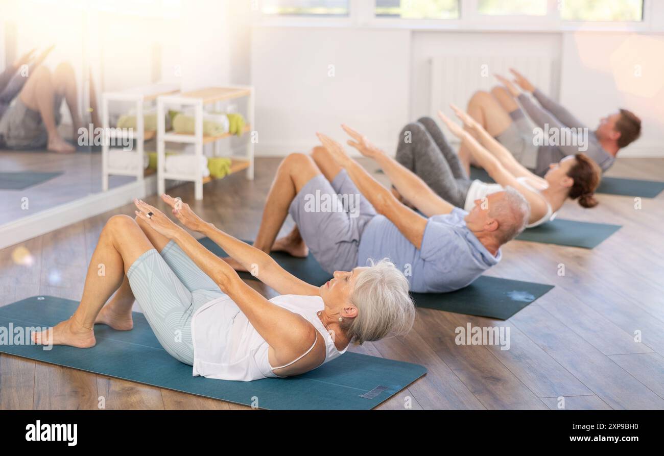 Elderly woman during group workout performs exercises to strengthen ...