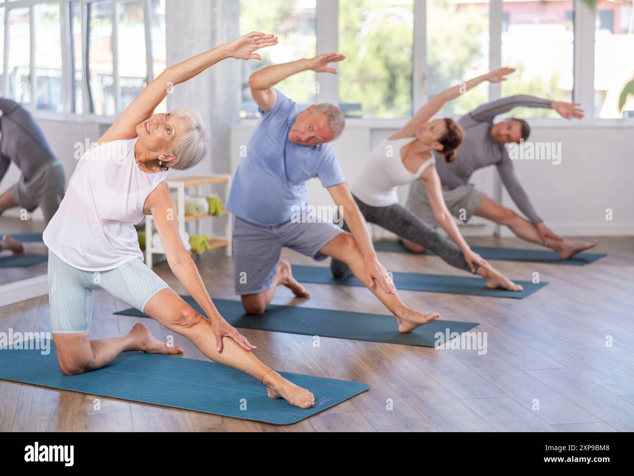 Mature female participant working out practice Parighasana, bolt pose ...