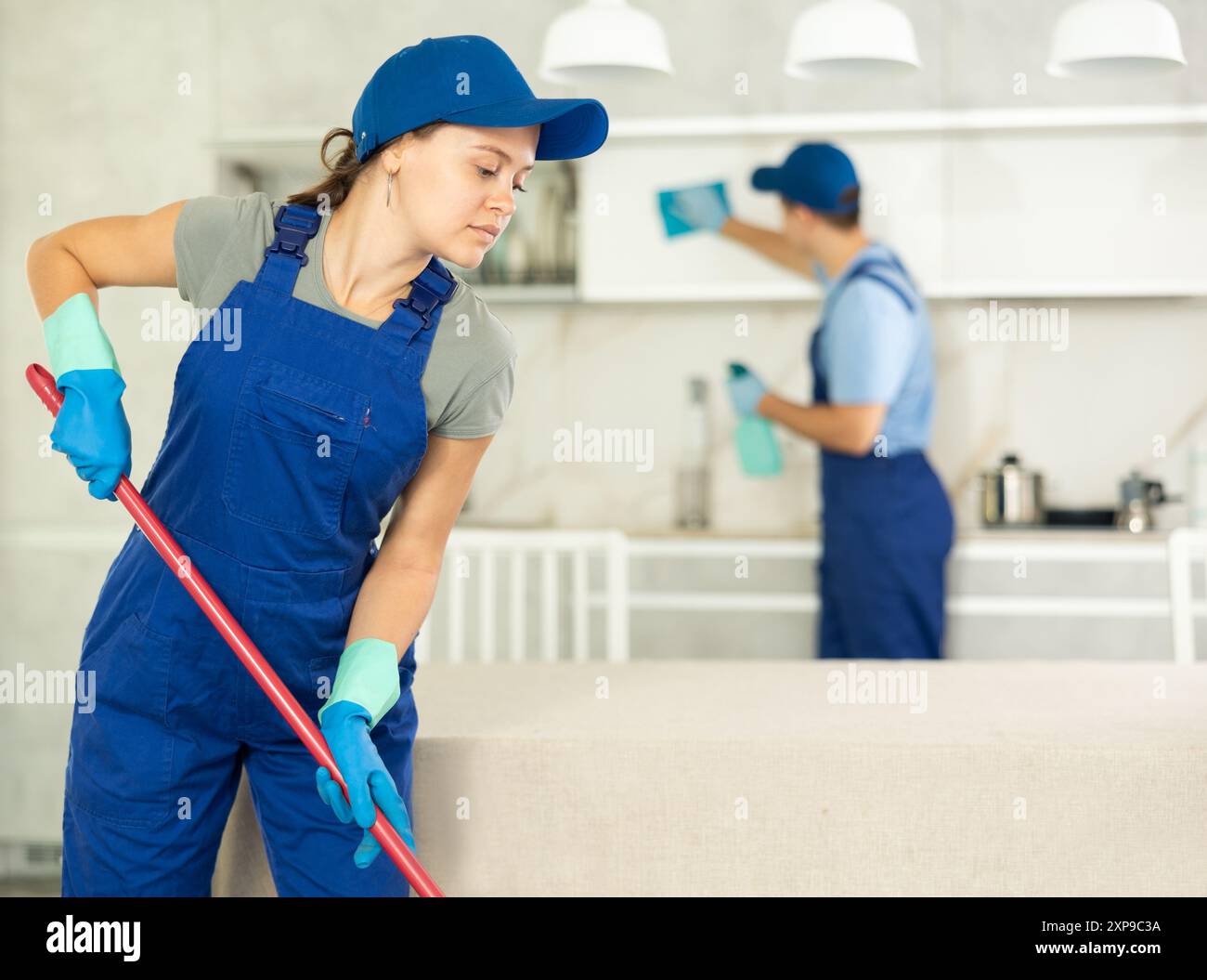 Girl employee of cleaning company in blue jumpsuit cleans and washes ...