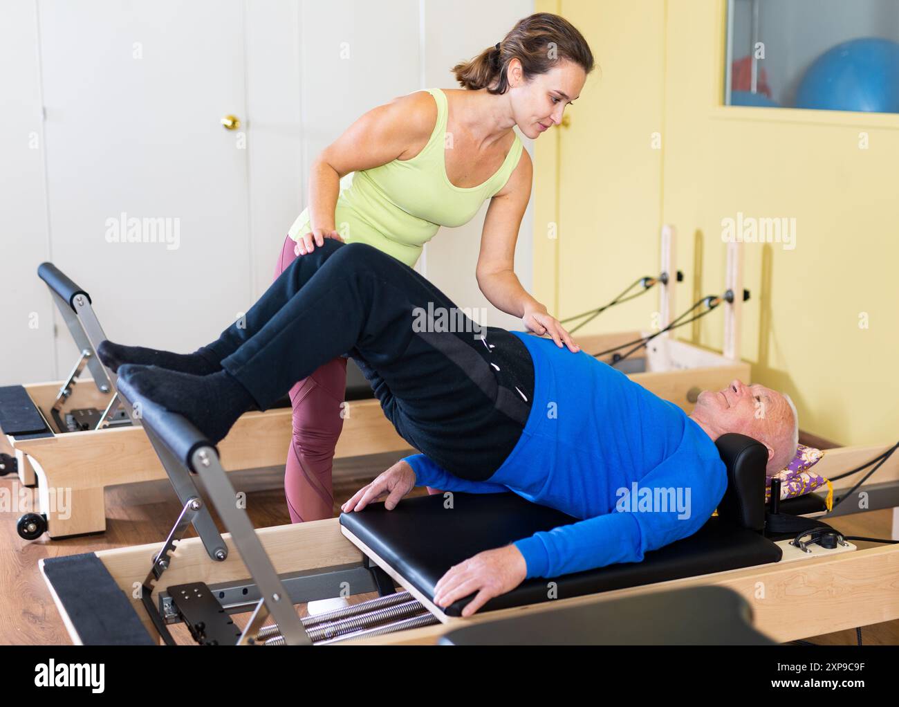 Female trainer controlling senior man doing pilates on reformer Stock ...