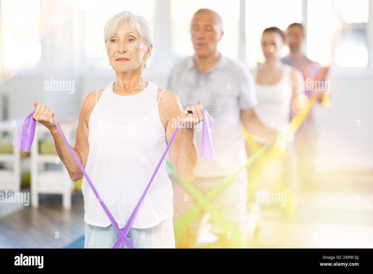 Elderly woman performs exercises with elastic band during Pilates ...