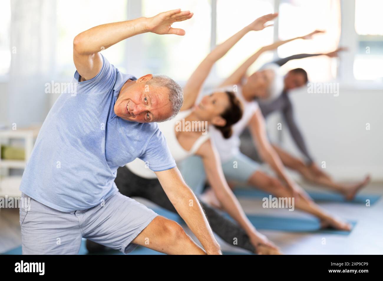Athletic mature women and men doing side bend, effective pose for back ...