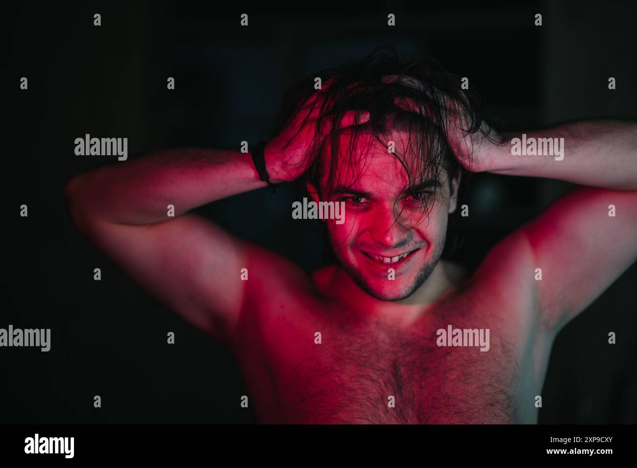 Confident young man with a playful smirk in moody red lighting Stock ...