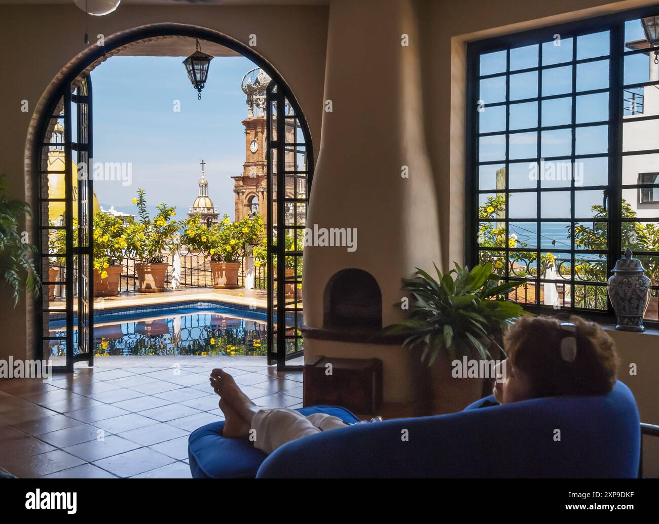 Woman napping in elegant villa overlooking swimming pool, Our Lady of Guadalupe steeple and Bay ...