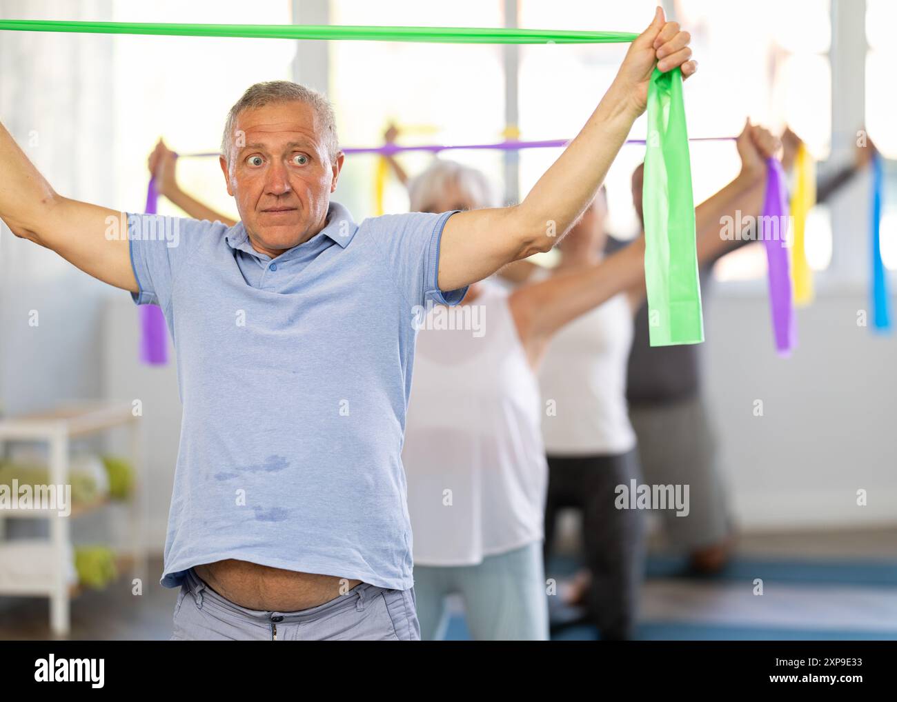 Group of seniors using resistance bands to stretch their arms and body ...