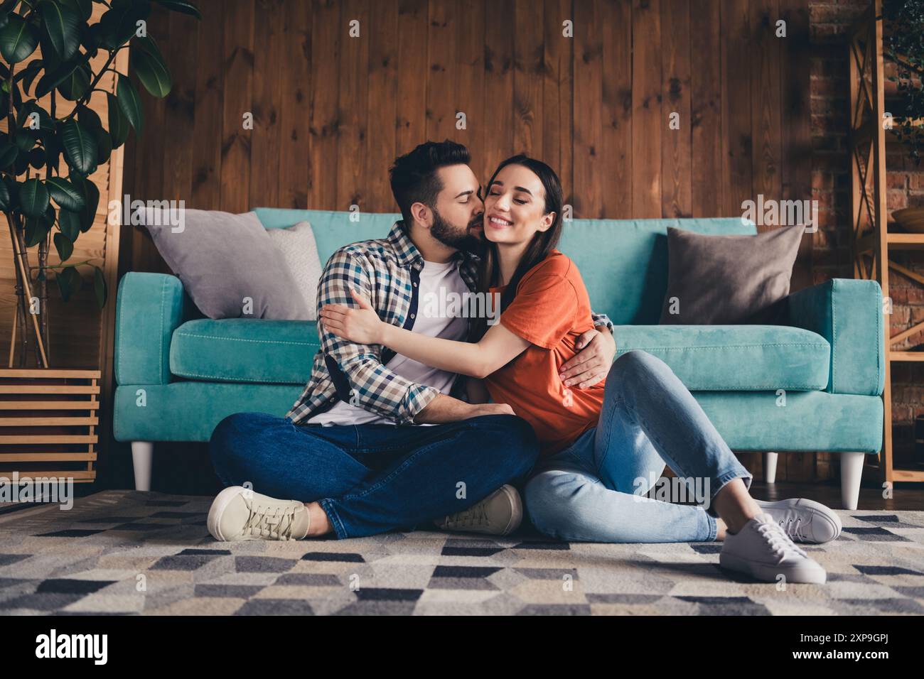 Full length photo of cheerful sit floor hug kiss cheek married young ...