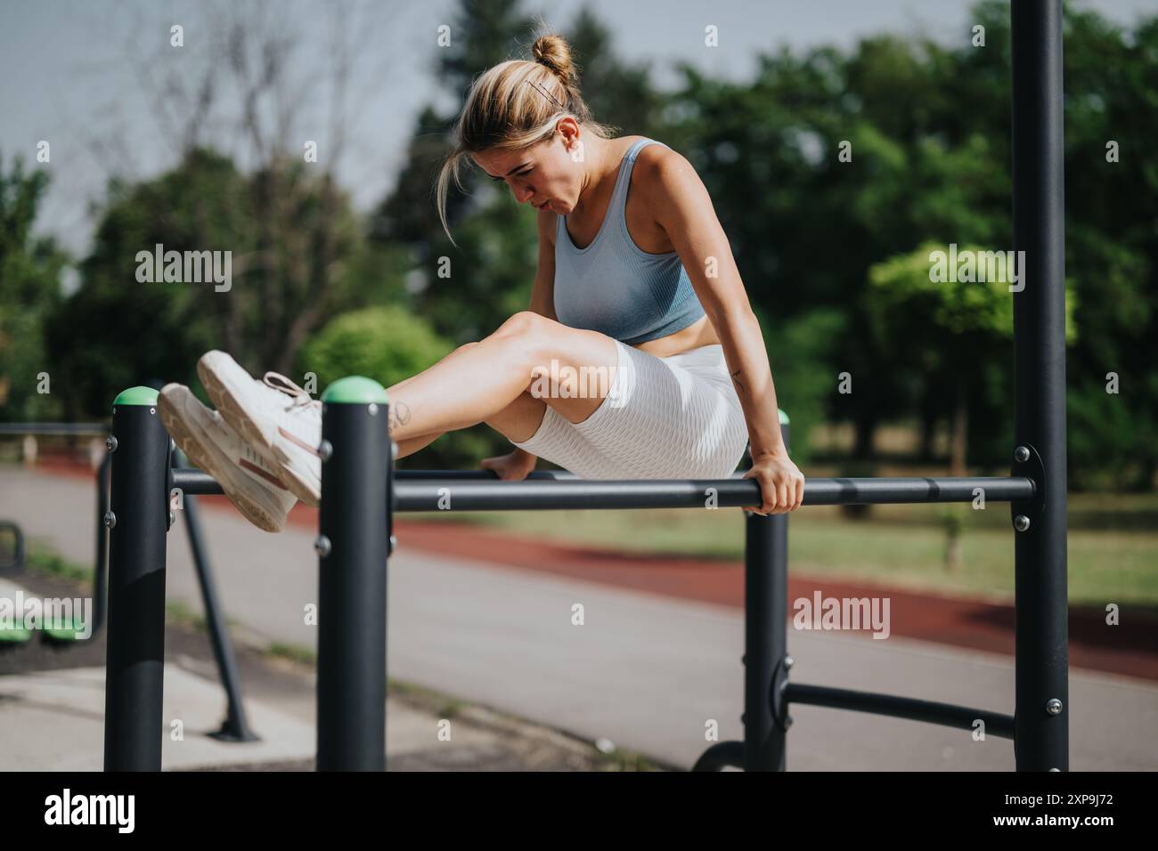 Woman performing calisthenics on parallel bars in a sunny park Stock ...