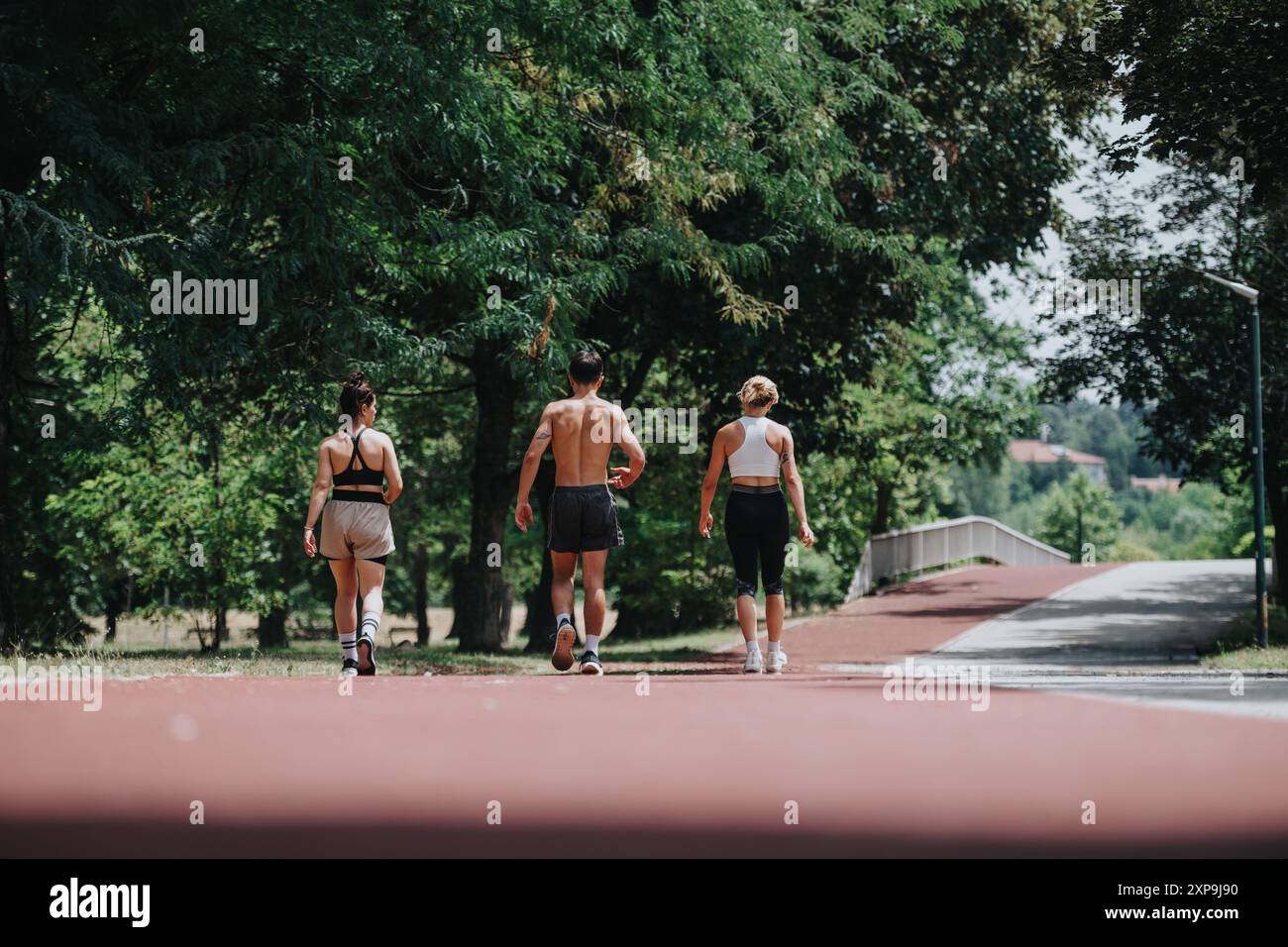 Group of people walking and jogging on a track in a park surrounded by ...