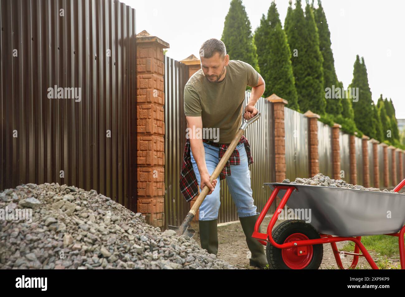 Man picking stones up with shovel and wheelbarrow outdoors Stock Photo ...