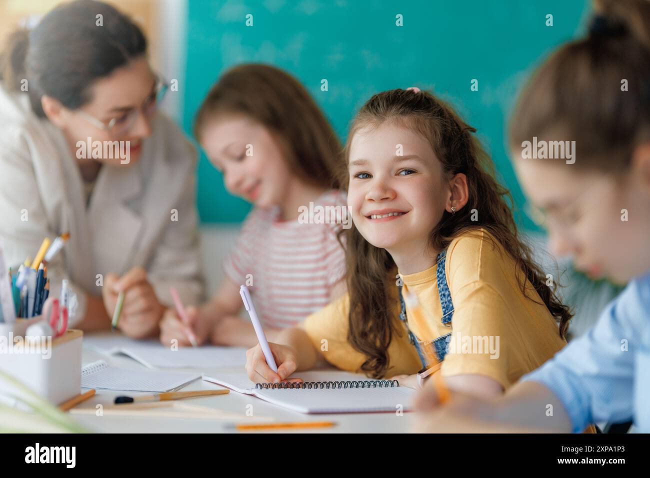 Happy kids and teacher at school. Woman and children are working in the ...