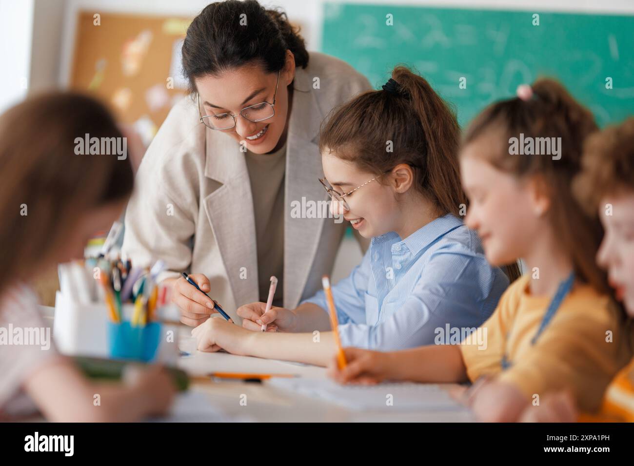 Happy kids and teacher at school. Woman and children are working in the ...
