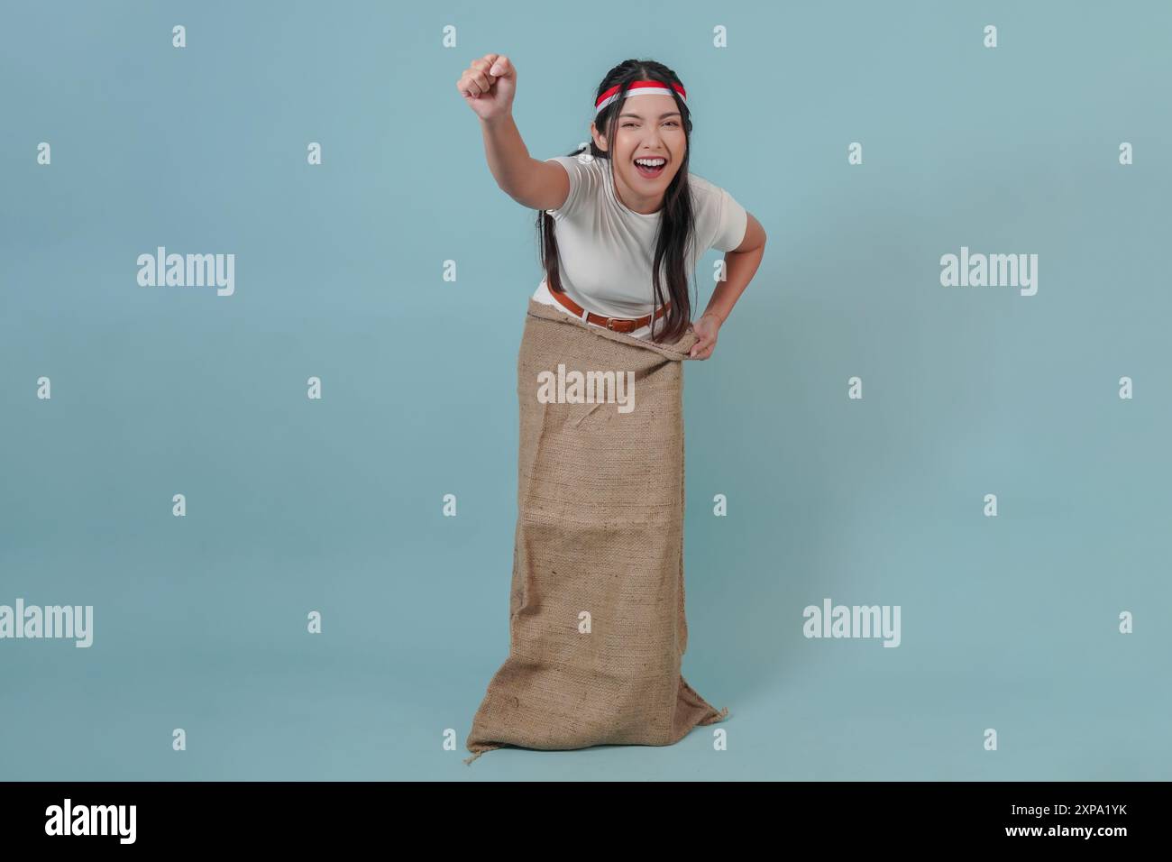 Happy Indonesian woman wearing gunny sack for competition, jumping ...